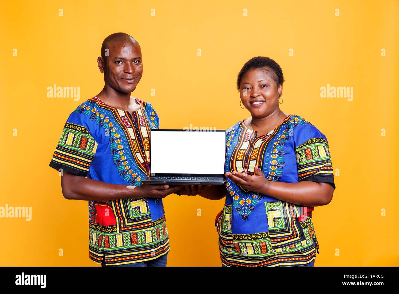 Smiling african american couple wearing ethnic clothes holding laptop ...