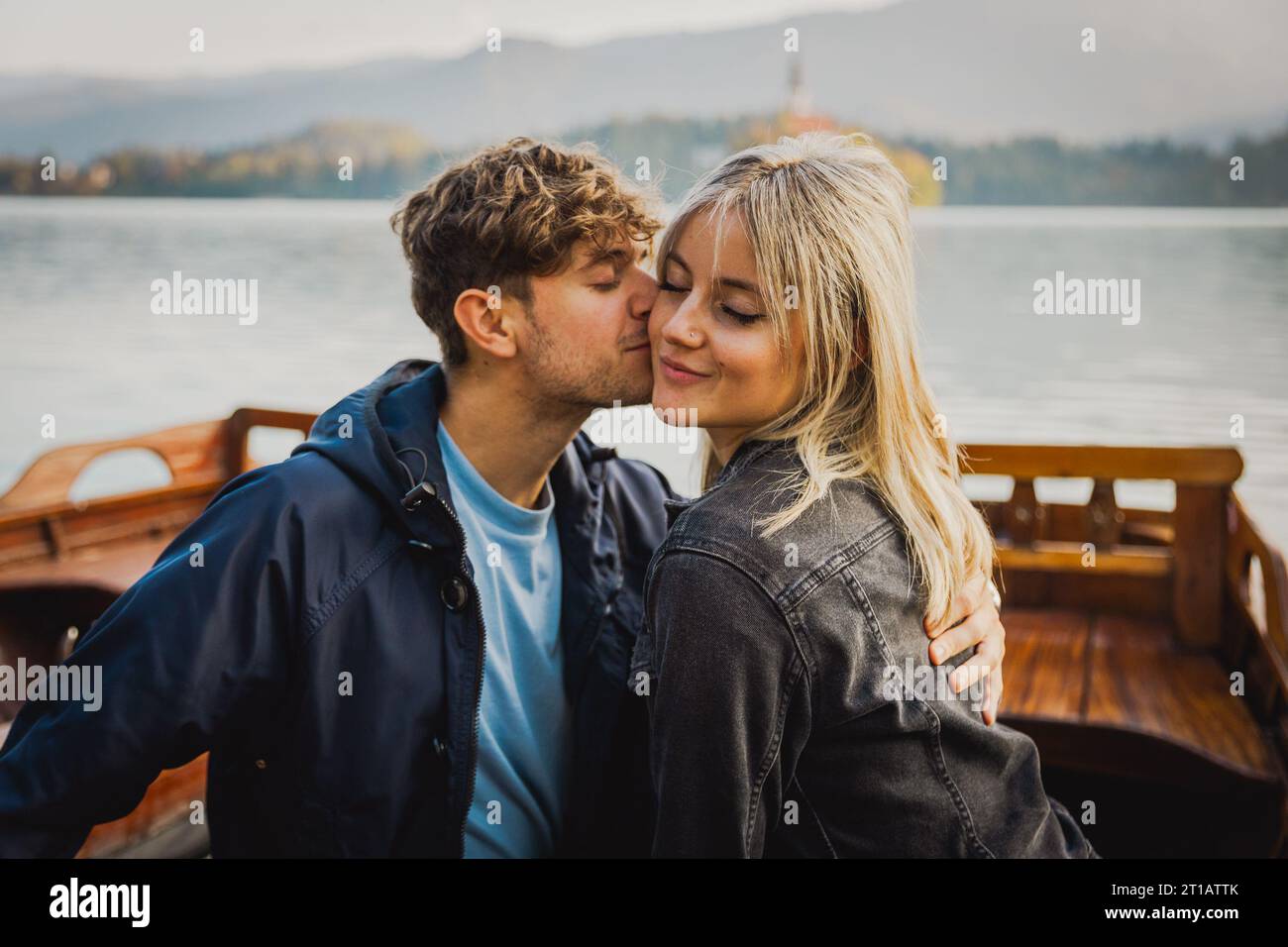 A man kisses his girlfriend on the cheek while they are on a boat, a ...