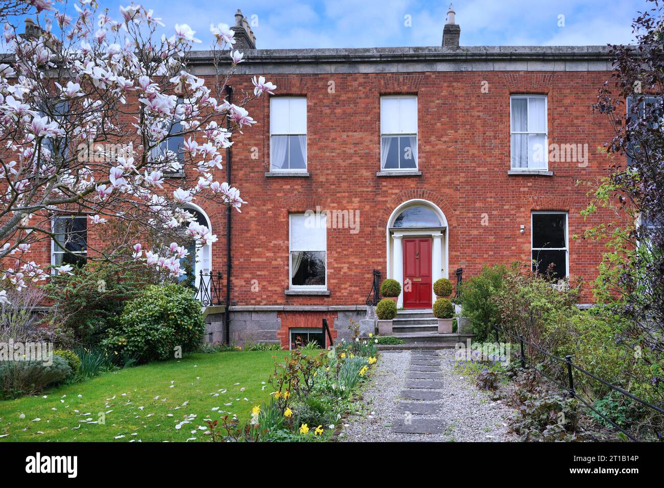 Brick townhouse with spring flowers in front garden Stock Photo - Alamy