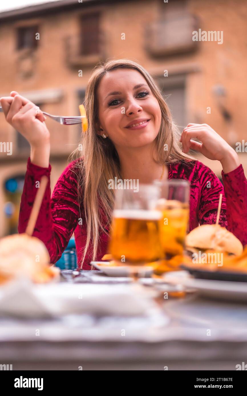Blonde woman eating lunch in a red dress next to a medieval castle ...