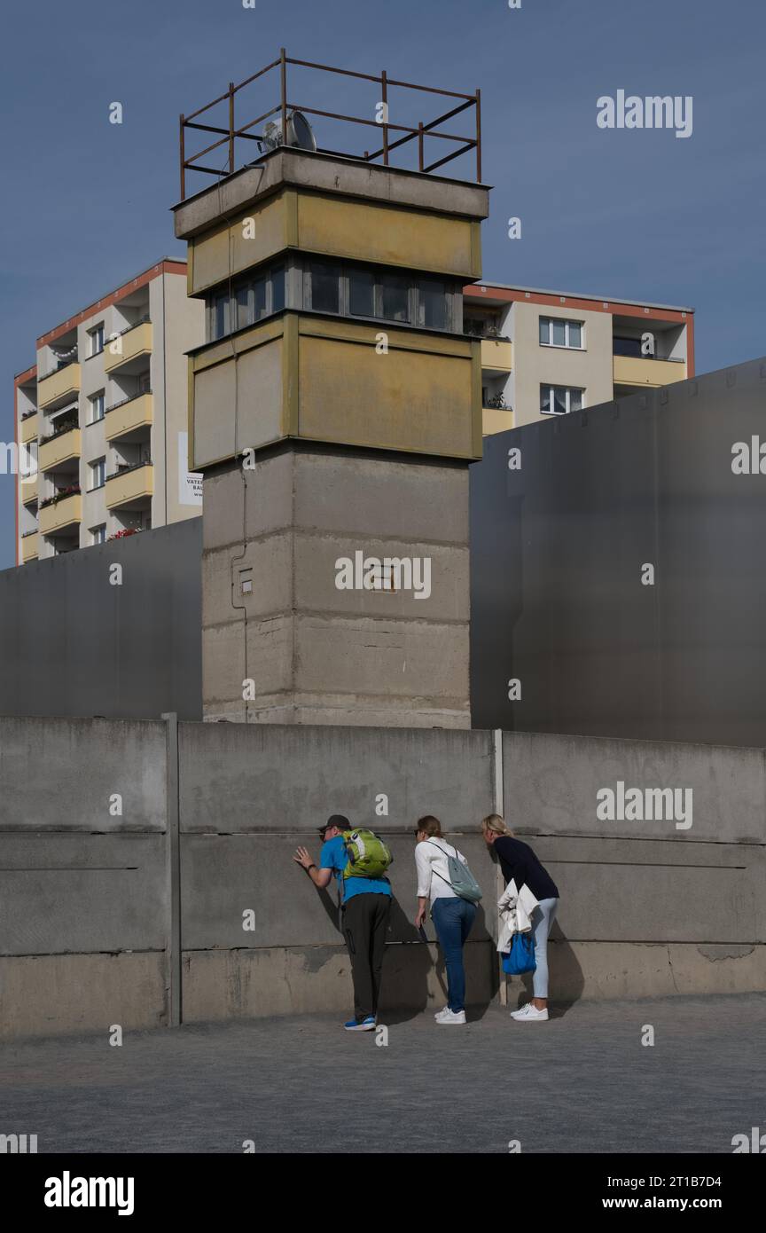 Visitors to the Wall memorial look through gaps between the concrete ...