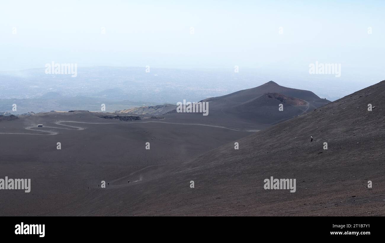 View of Mt. Etna and dark volcanic ash with blue sky and white clouds ...