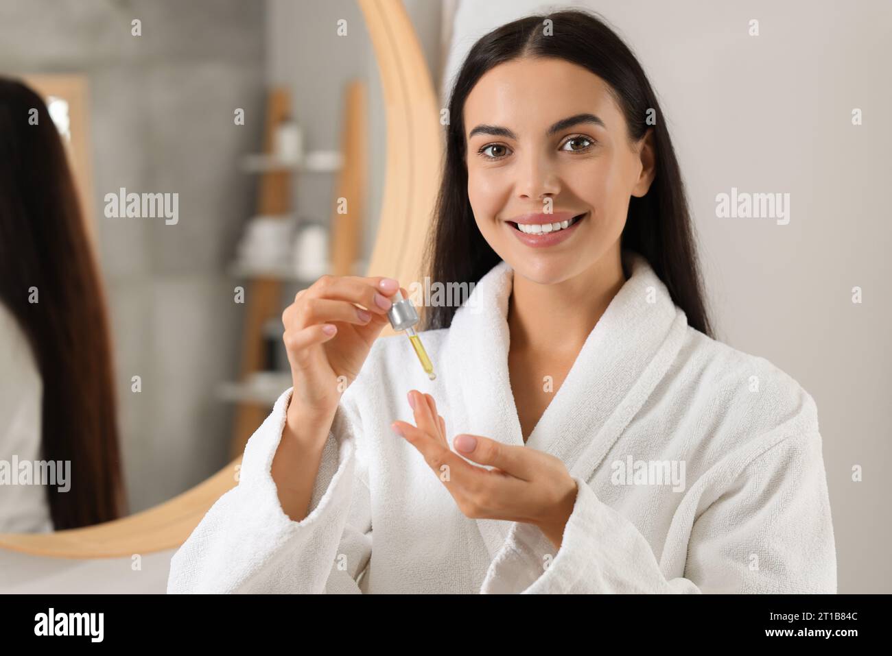 Young woman applying serum onto her hand in bathroom Stock Photo - Alamy