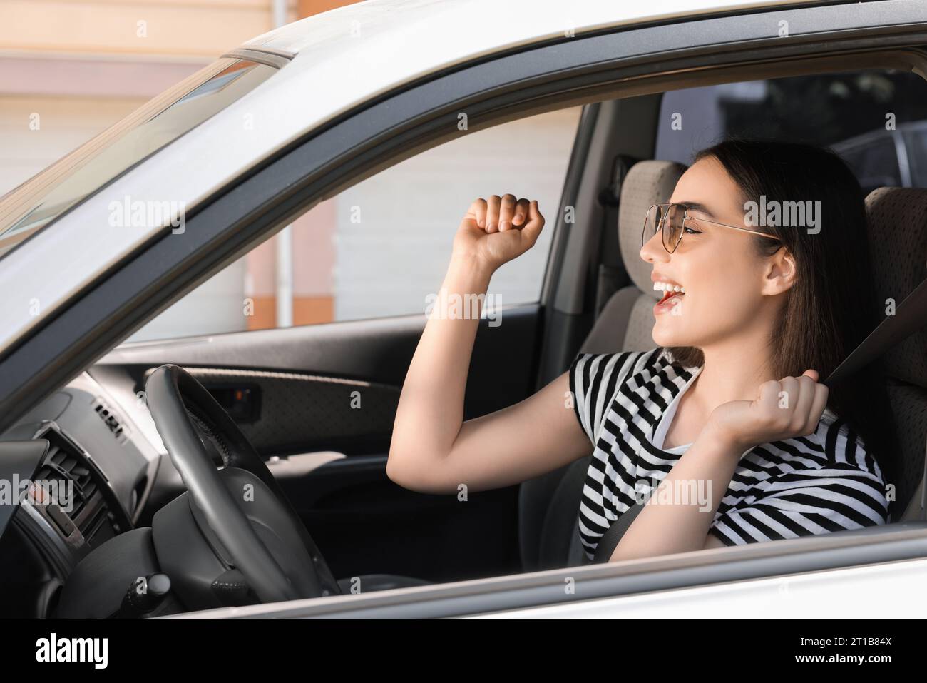 Listening to radio while driving. Beautiful young woman with stylish ...