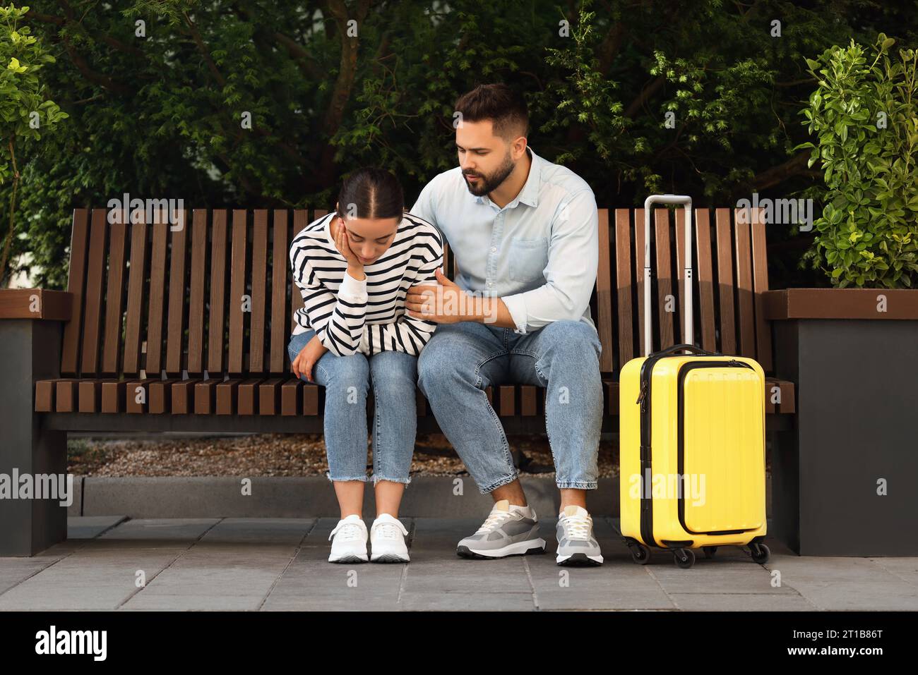 Long-distance relationship. Man calming his sad girlfriend on bench and ...