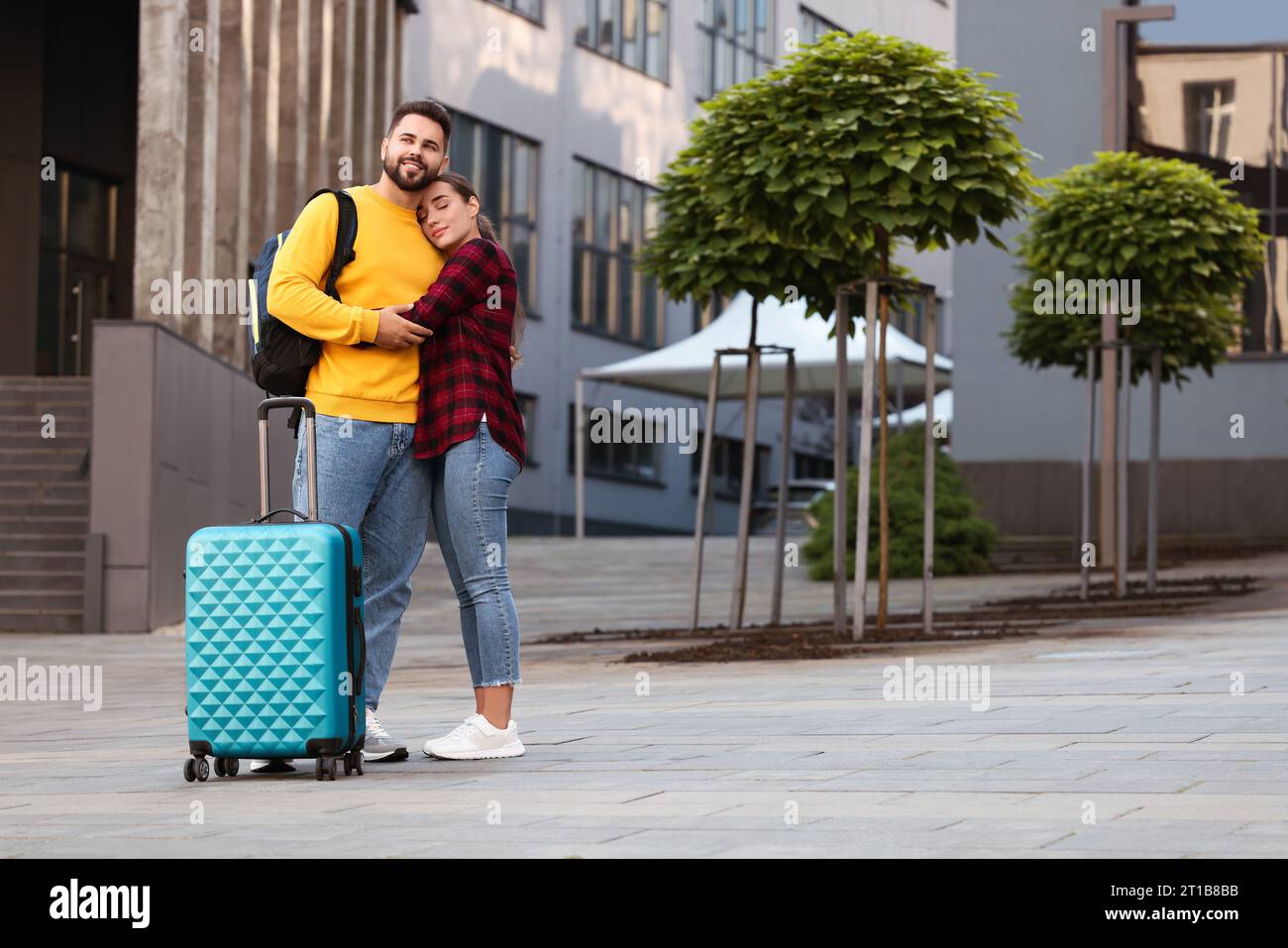Long-distance relationship. Beautiful young couple with luggage hugging ...