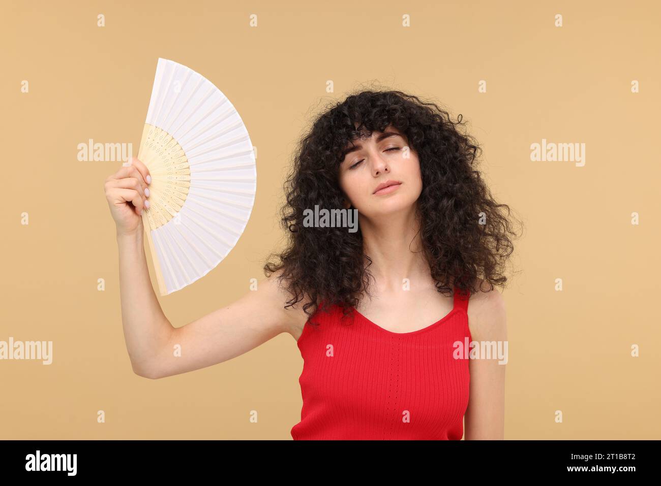 Woman with hand fan suffering from heat on beige background Stock Photo ...