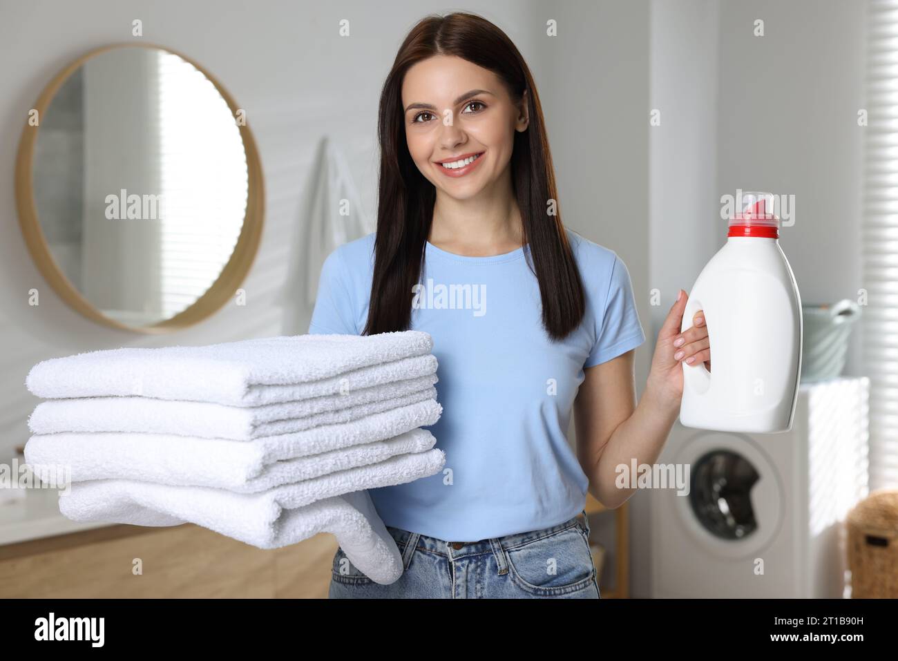 Woman holding clean towels and fabric softener in bathroom Stock Photo - Alamy