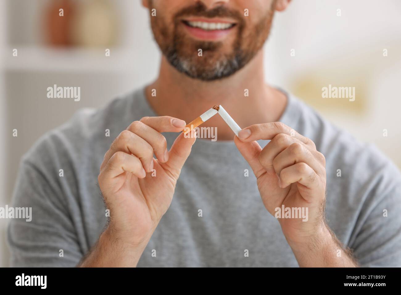 Stop smoking concept. Man breaking cigarette on blurred background ...