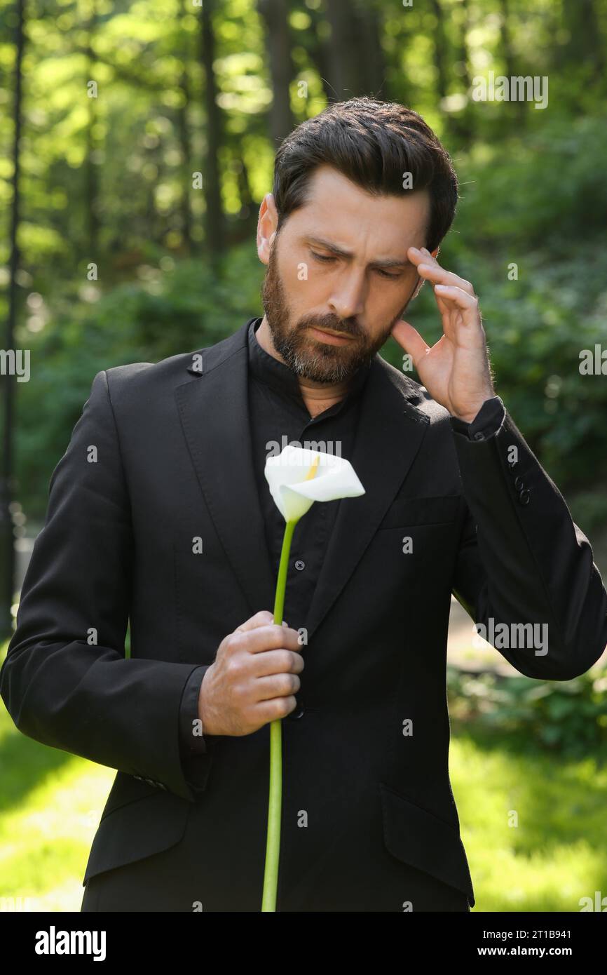 Sad man with calla lily flower outdoors. Funeral ceremony Stock Photo ...