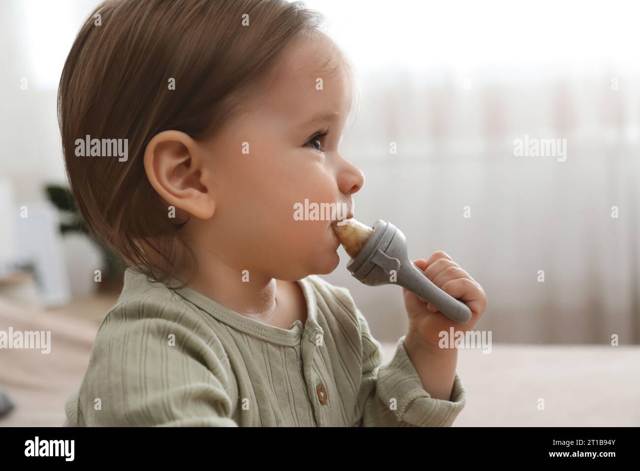 Cute baby girl with nibbler at home Stock Photo - Alamy