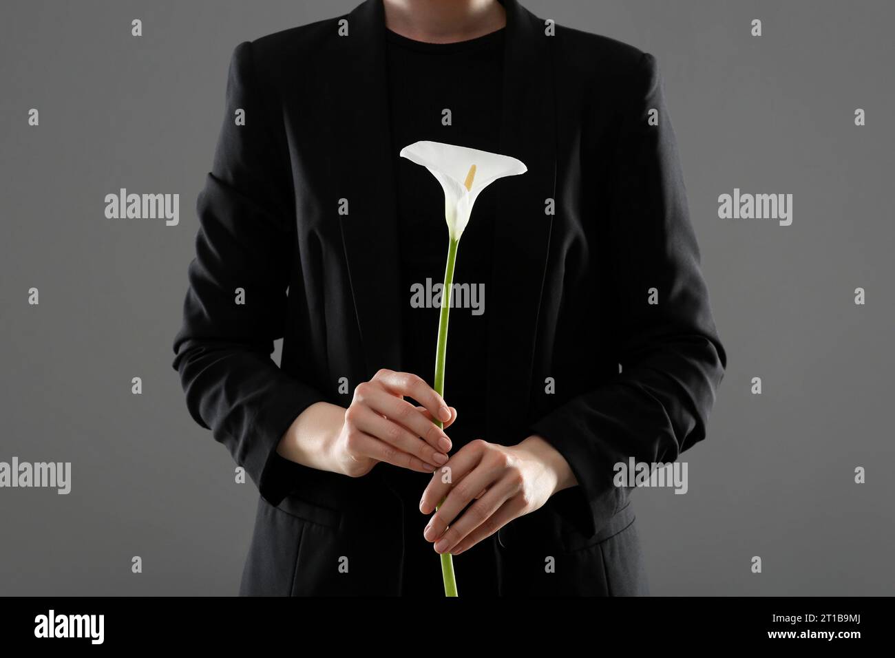 Woman with calla lily flower on grey background, closeup. Funeral ...
