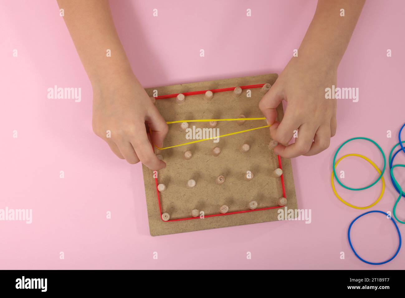 Motor skills development. Girl playing with geoboard and rubber bands ...