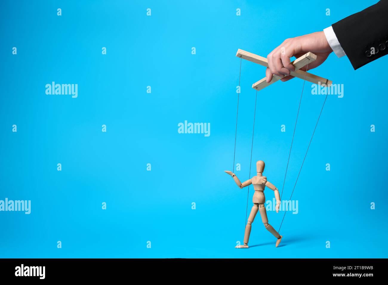 Man pulling strings of puppet on light blue background, closeup. Space ...