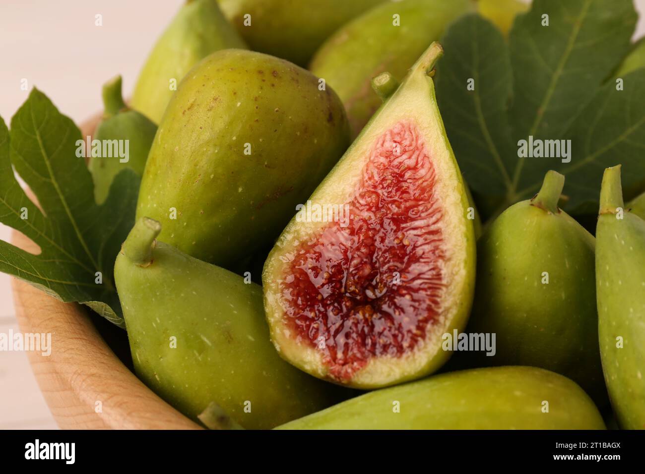 Cut and whole fresh green figs in wooden bowl, closeup Stock Photo - Alamy