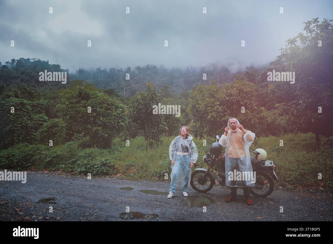 couples of asian biker wearing plastic raincoat stainding beside small ...