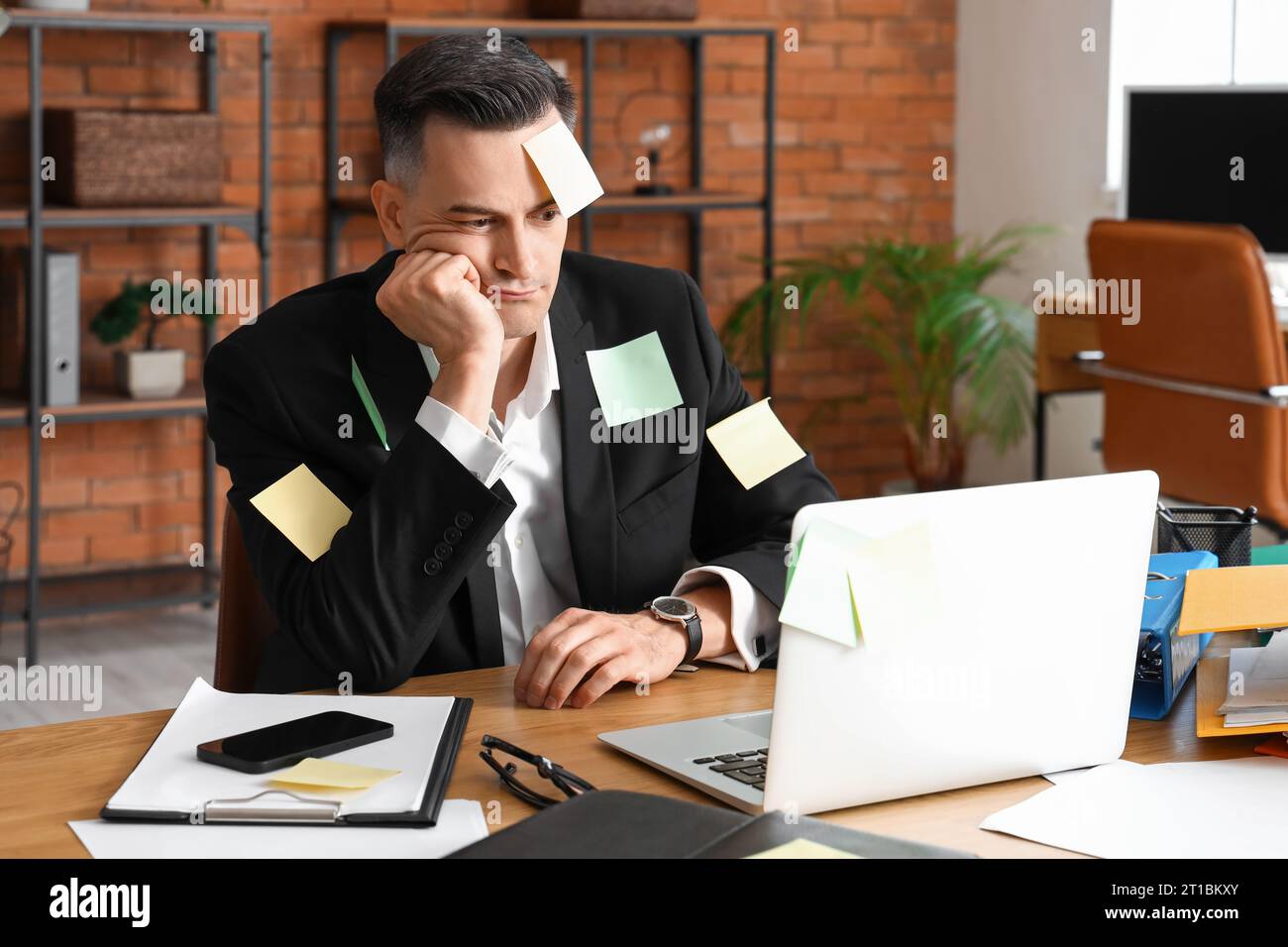 Stressed businessman with sticky notes working under deadline in office ...
