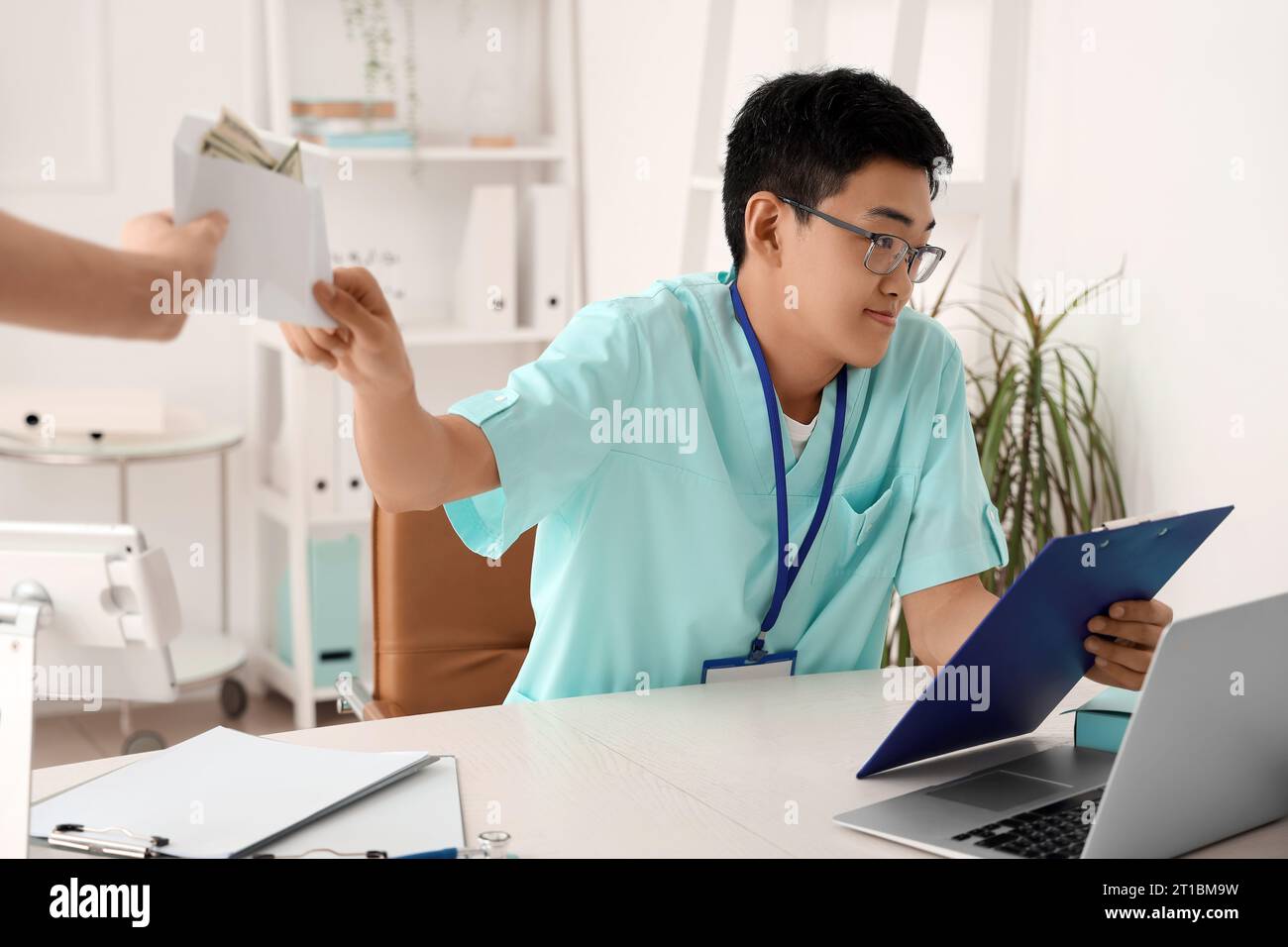 Male Asian doctor taking bribe in clinic Stock Photo - Alamy