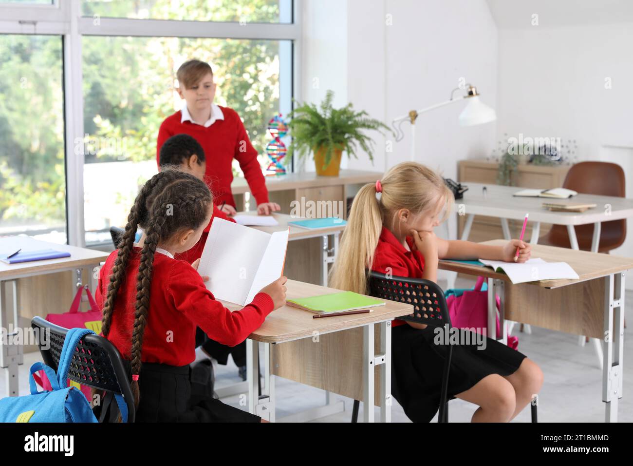 Little classmates sitting at desks in classroom Stock Photo - Alamy