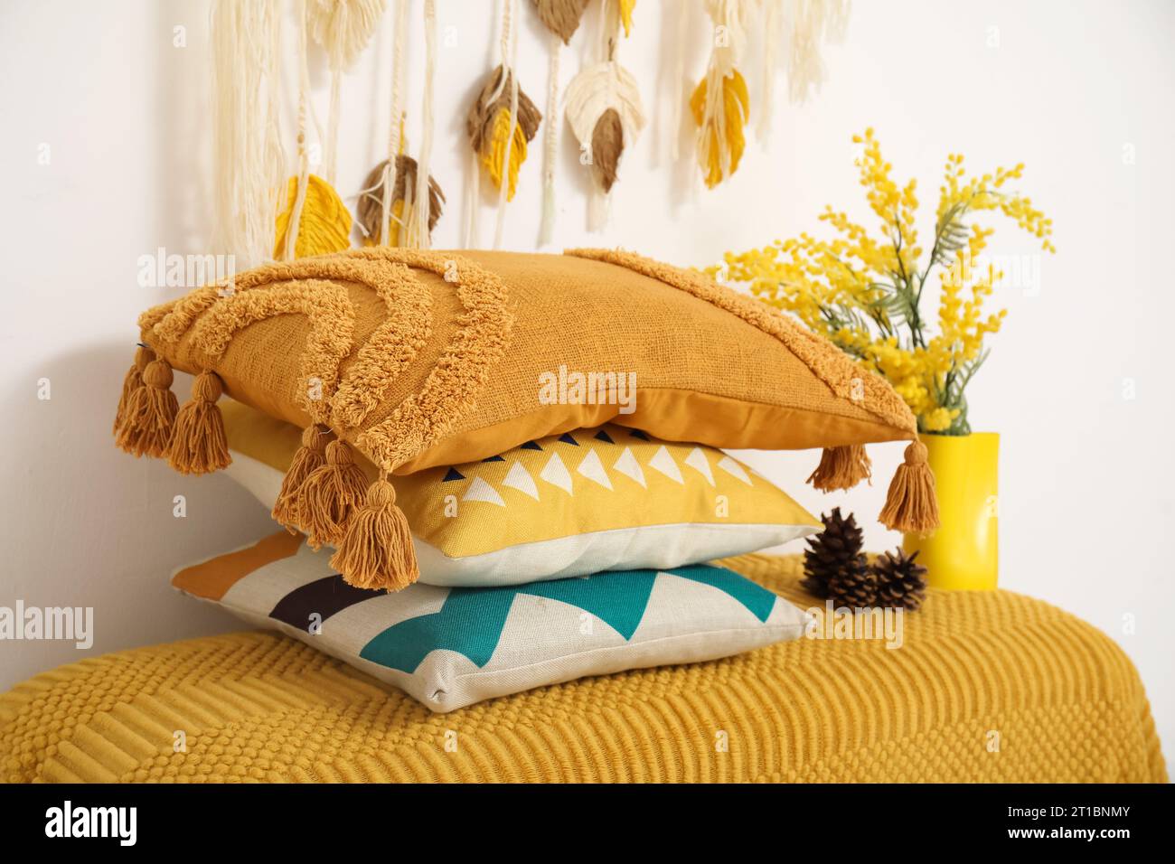 Stack of soft pillows with vase of flowers and pine cones on coffee ...