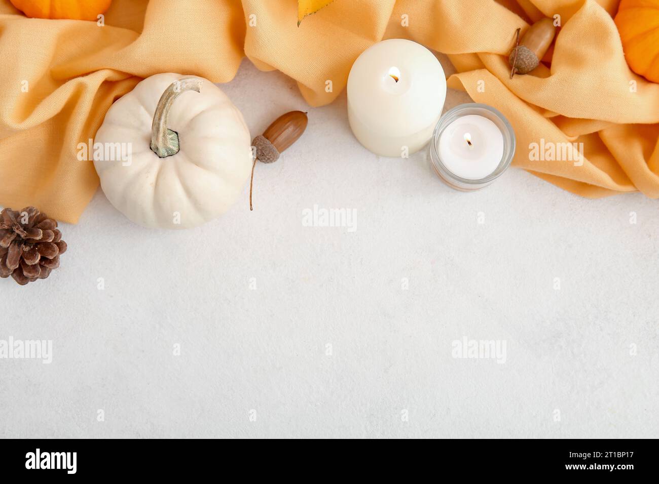 Burning candles with scarf, pine cone, pumpkin and acorns on white ...