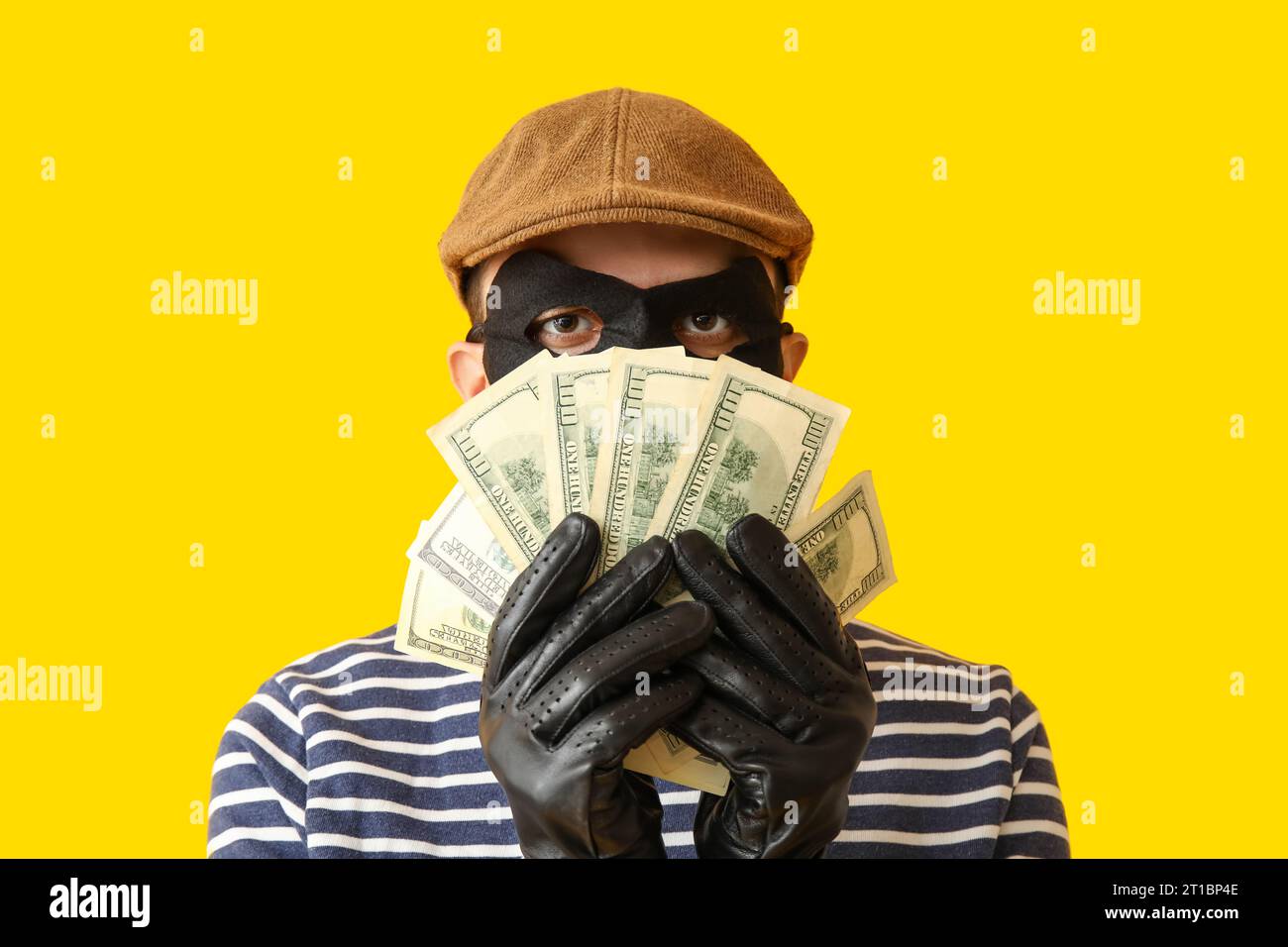 Male thief with dollar banknotes on yellow background Stock Photo - Alamy