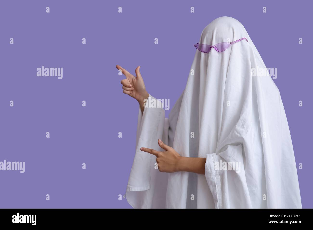 Woman in Halloween costume of ghost and sunglasses pointing at ...