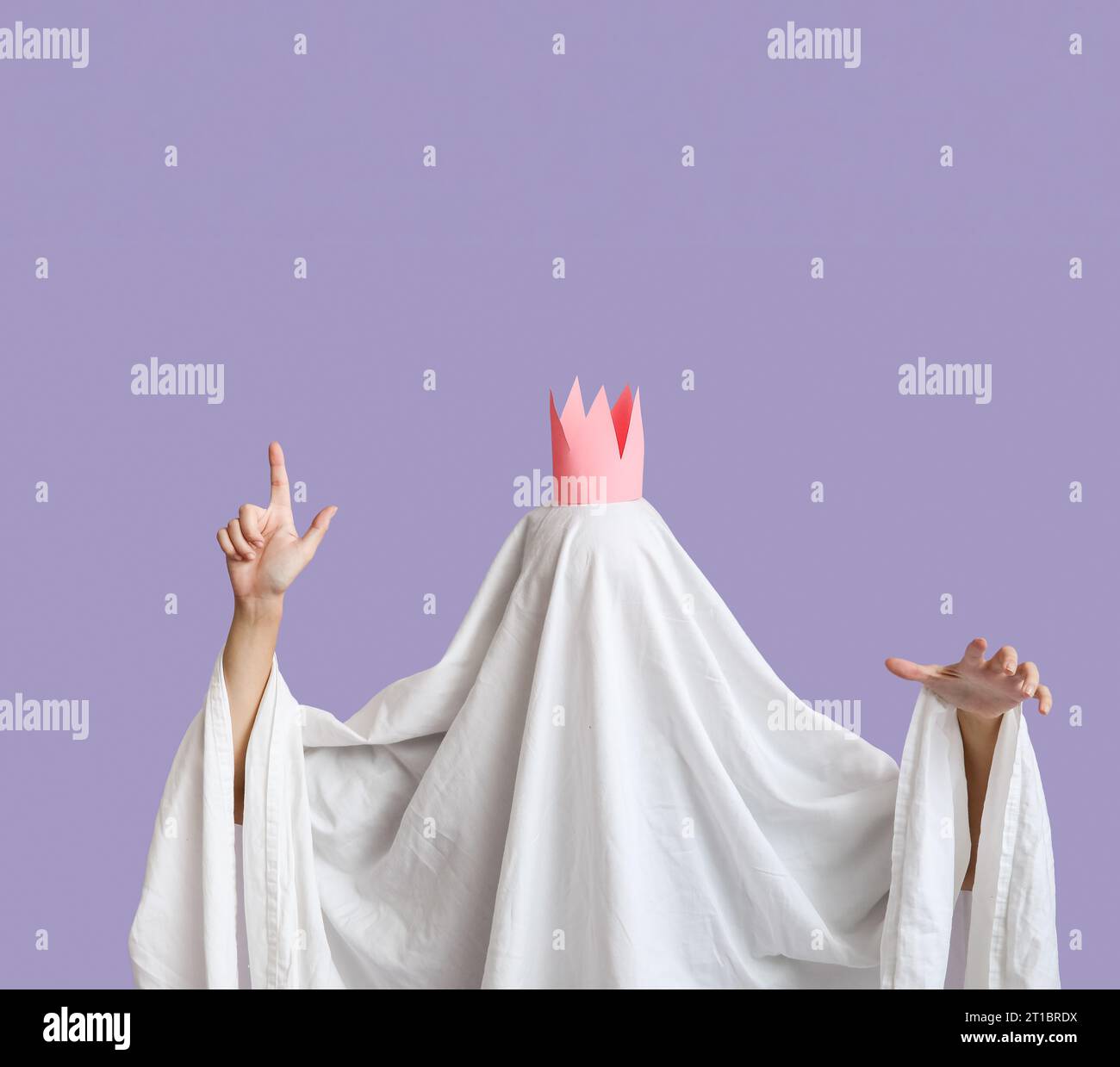 Woman in Halloween costume of ghost and paper crown pointing at ...