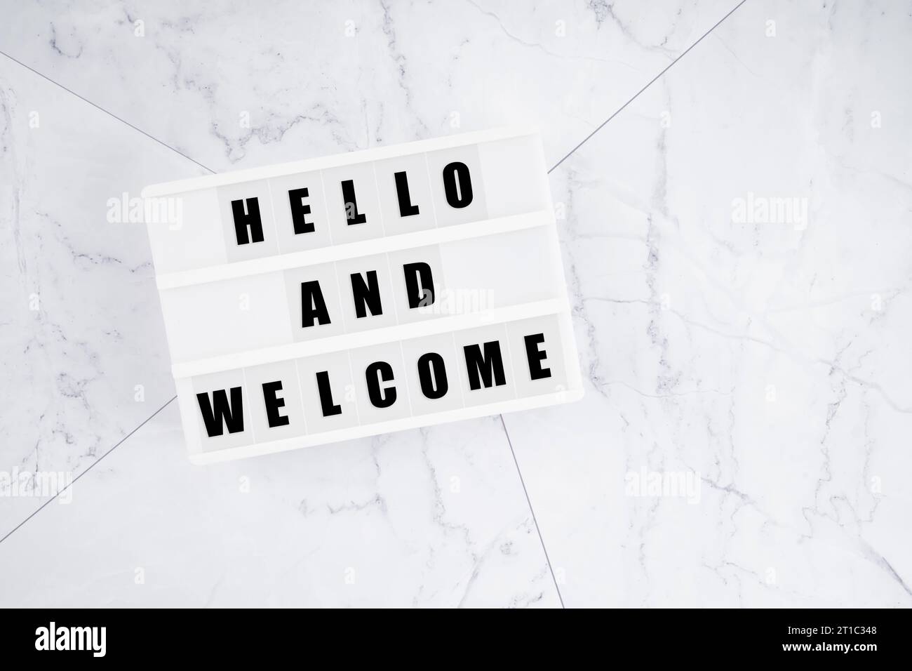 Hello and welcome written white lightbox sitting on white marble ...