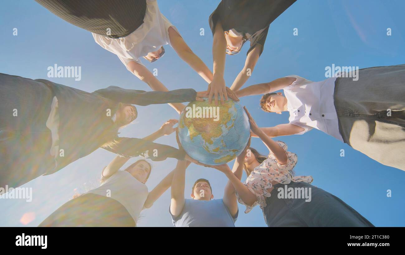 Friends holding a geographical globe in their hands. The concept of ...
