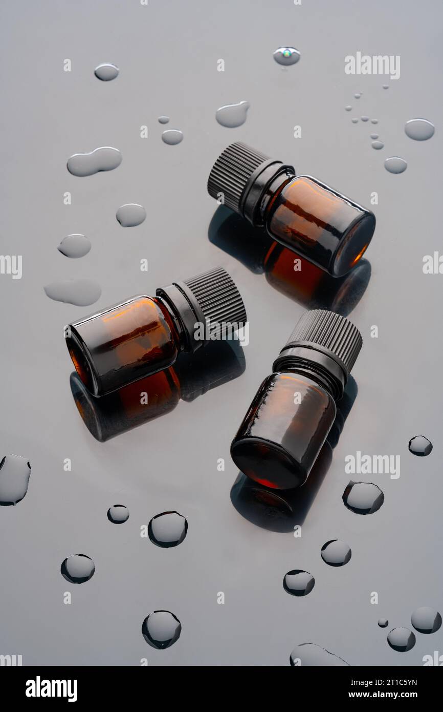 Three amber color small glass bottles on black background with water ...