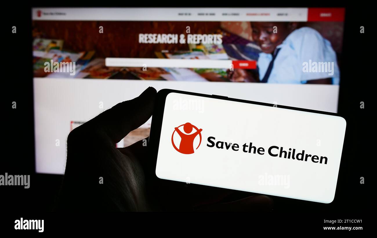 Person holding mobile phone with logo of charity organization Save the ...
