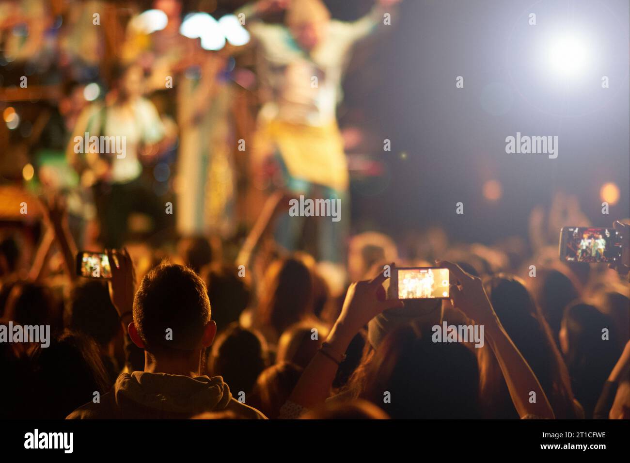 Audience with hands raised at a music festival and lights streaming ...