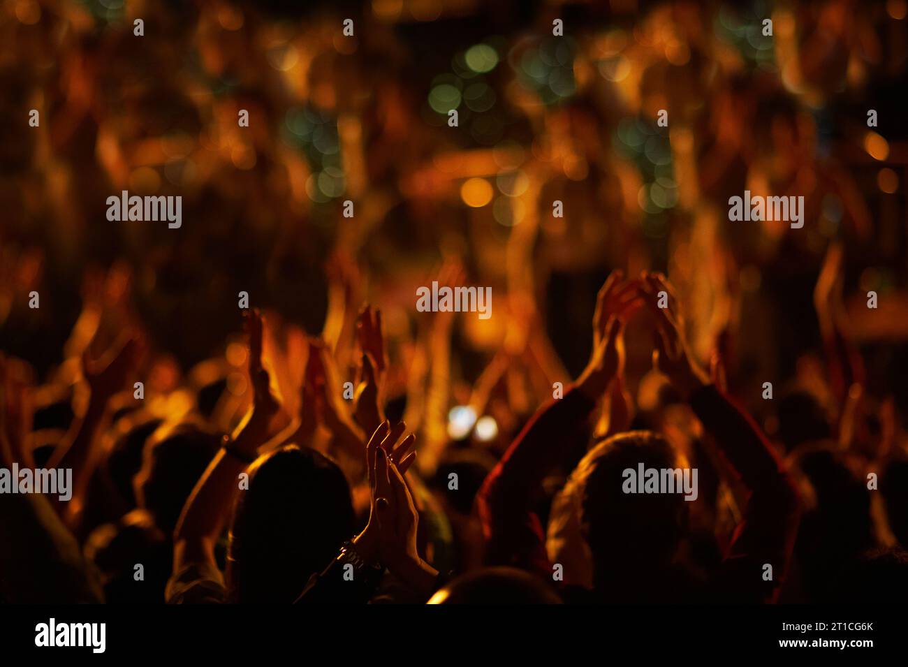 Audience with hands raised at a music festival and lights streaming ...