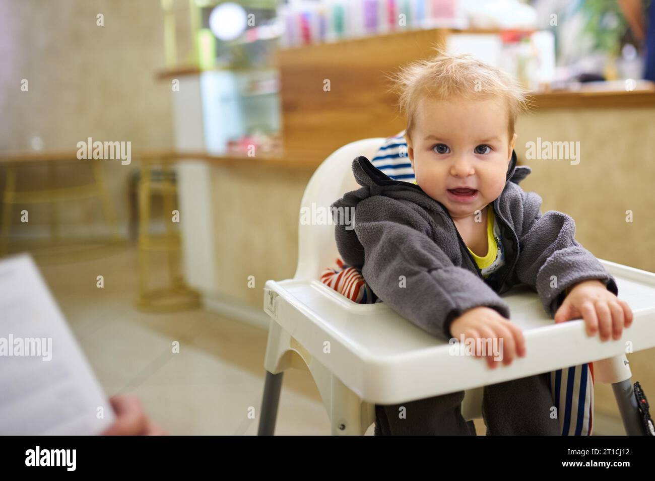 Little baby boy sitting in high chair in cafe Stock Photo - Alamy
