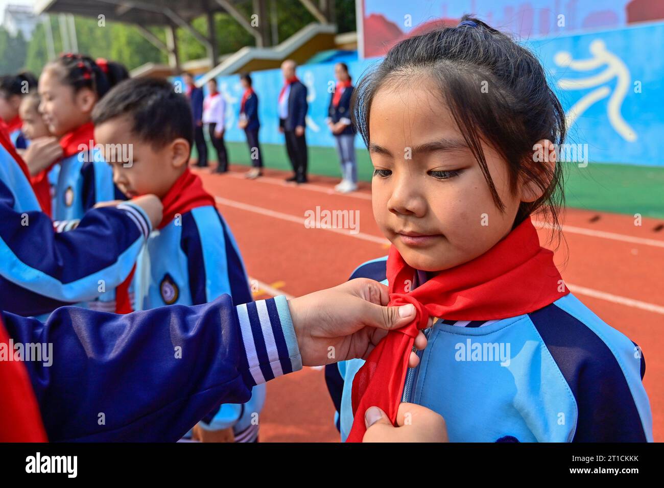QINGZHOU, CHINA - OCTOBER 13, 2023 - A teacher arranges the red scarf ...