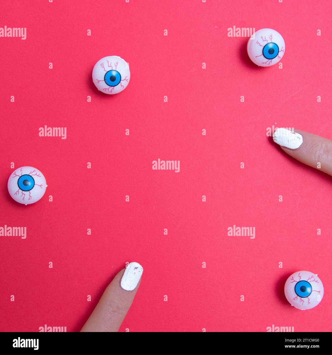 Creepy eyes together with creepy fingers on a red background with copy ...