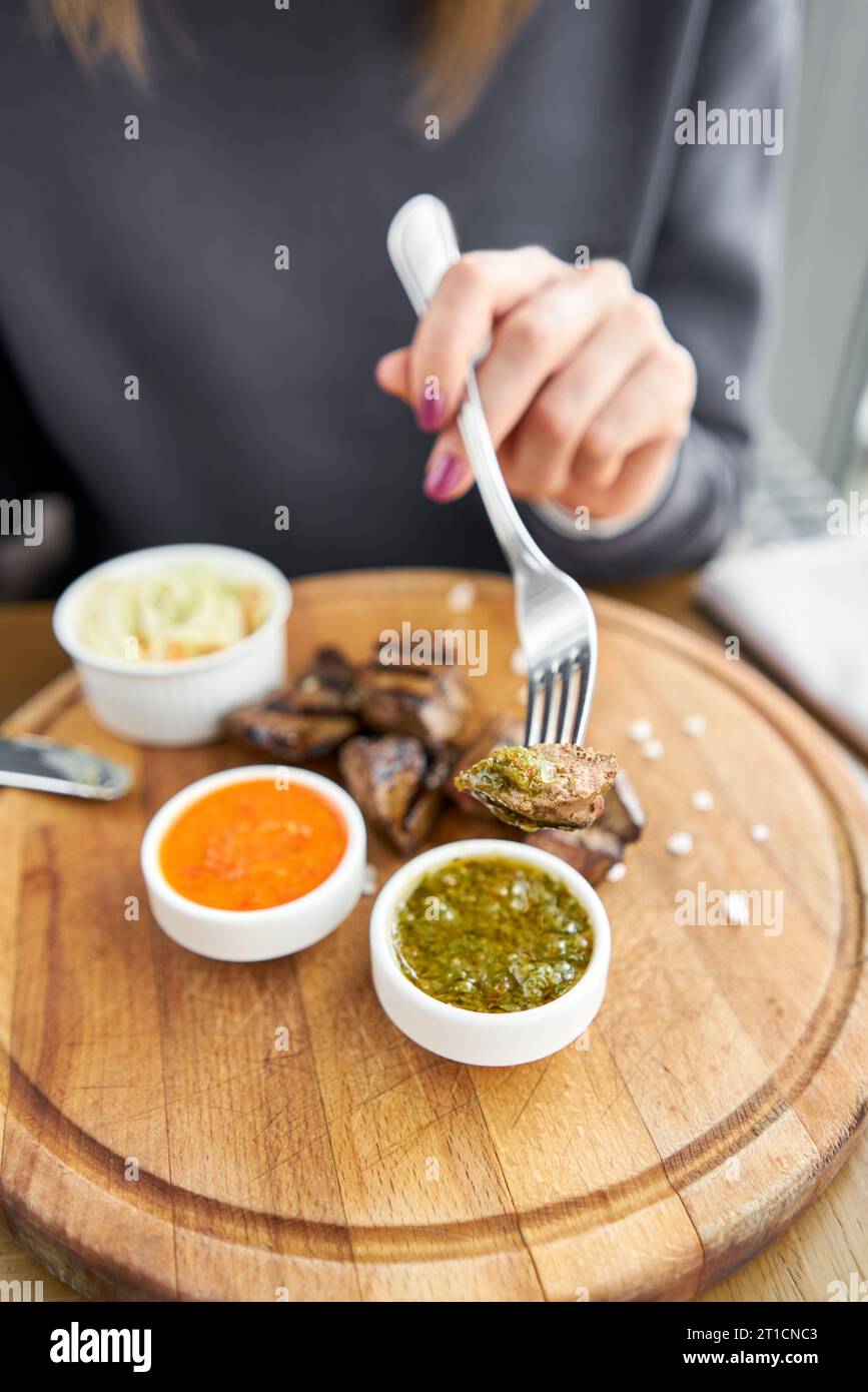 Lunch in a restaurant, a woman eats Pieces of liver cooked on the grill ...