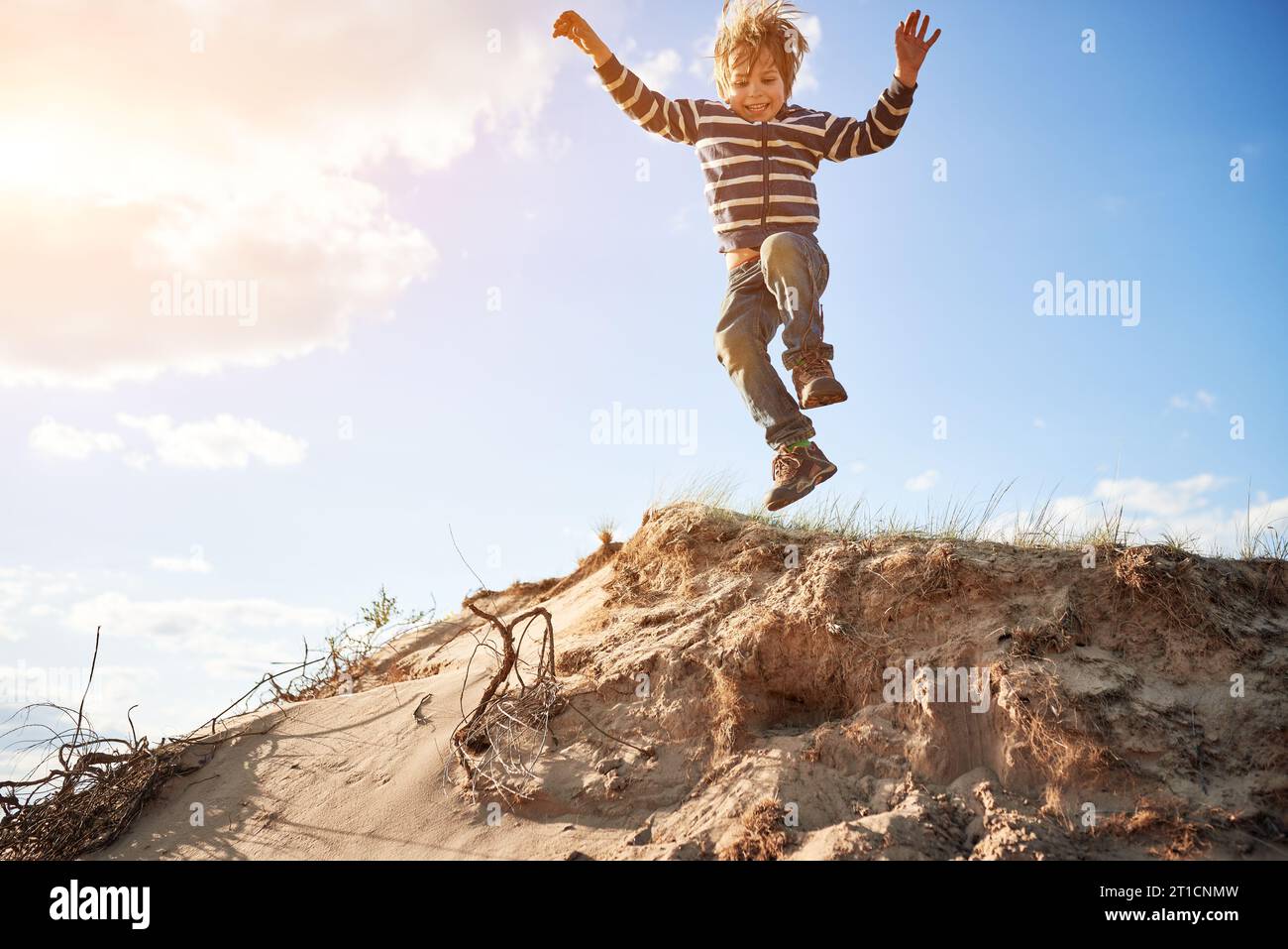 Happy boy jumping on sand at sunny day Stock Photo - Alamy