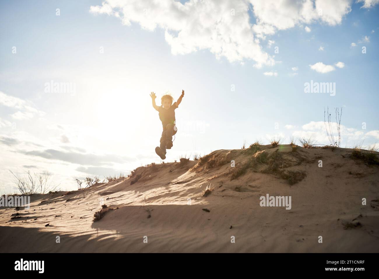 Happy boy jumping on sand at sunny day Stock Photo - Alamy