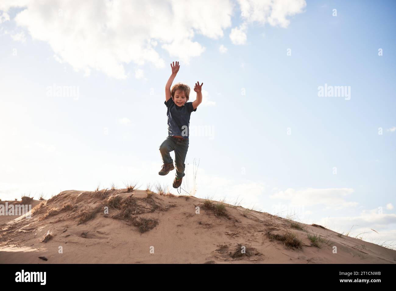 Happy boy jumping on sand at sunny day Stock Photo - Alamy