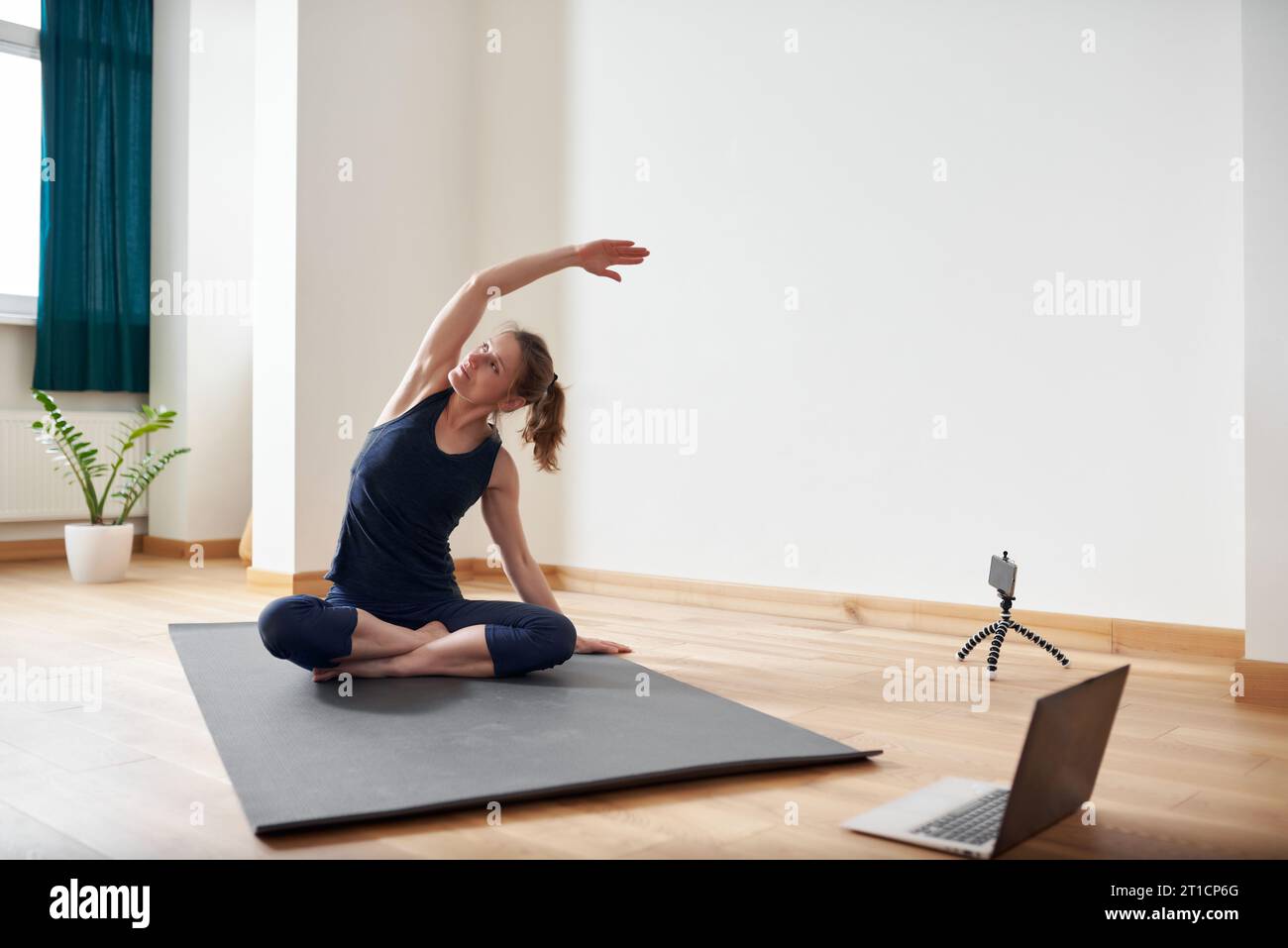 Woman doing yoga online. Computer and camera in her living room ...