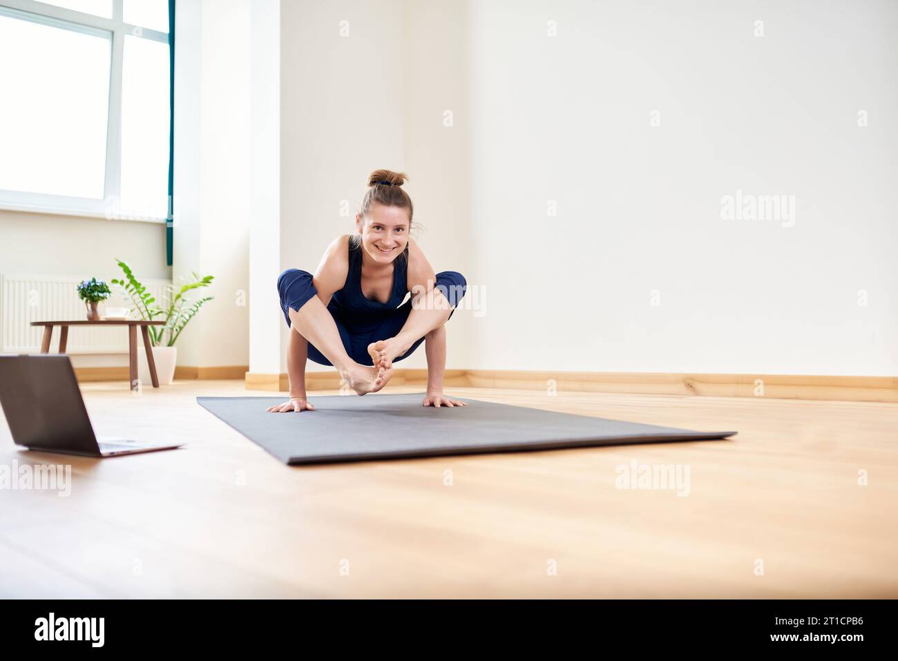 Woman doing yoga online. Computer and camera in her living room ...