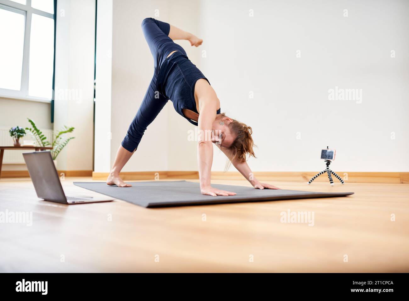 Woman doing yoga online. Computer and camera in her living room ...