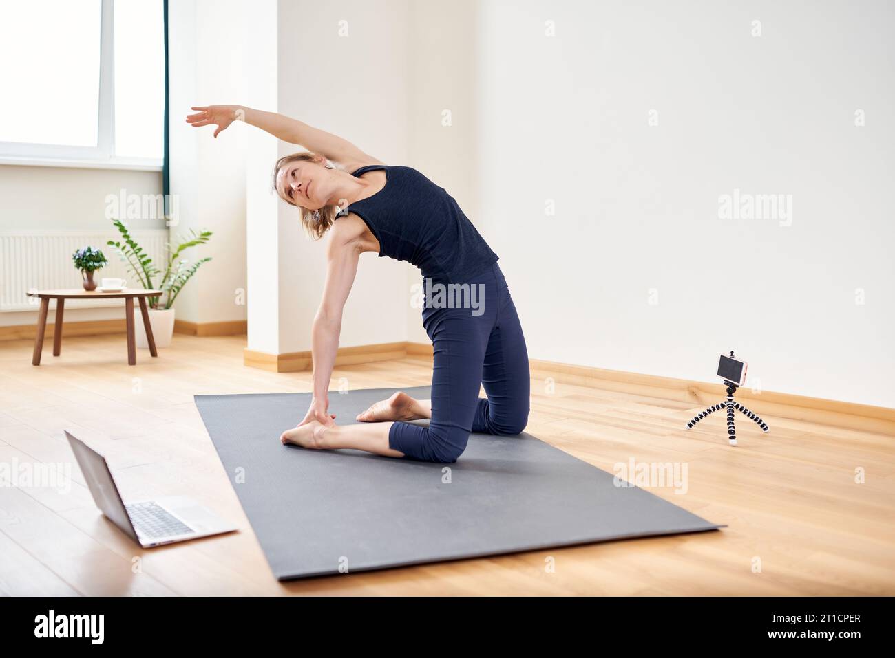 Woman doing yoga online. Computer and camera in her living room ...