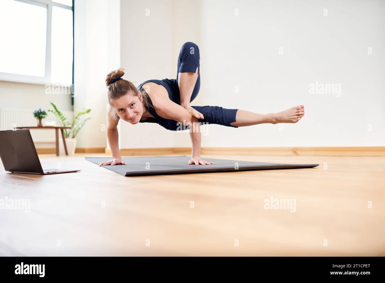 Woman doing yoga online. Computer and camera in her living room ...