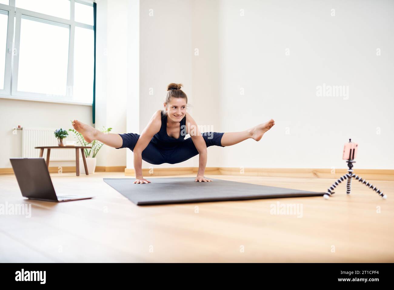 Woman doing yoga online. Computer and camera in her living room ...