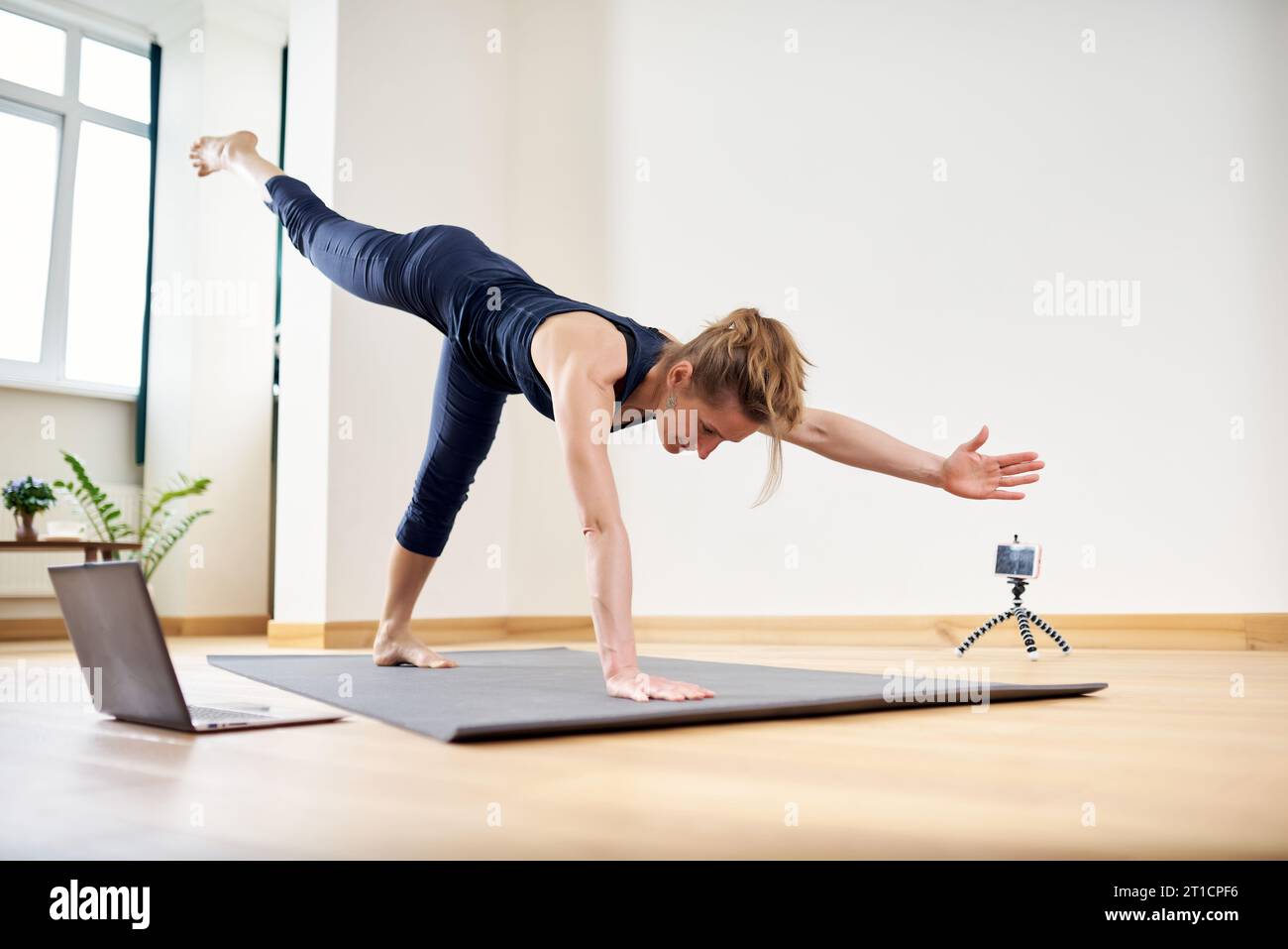 Woman doing yoga online. Computer and camera in her living room ...