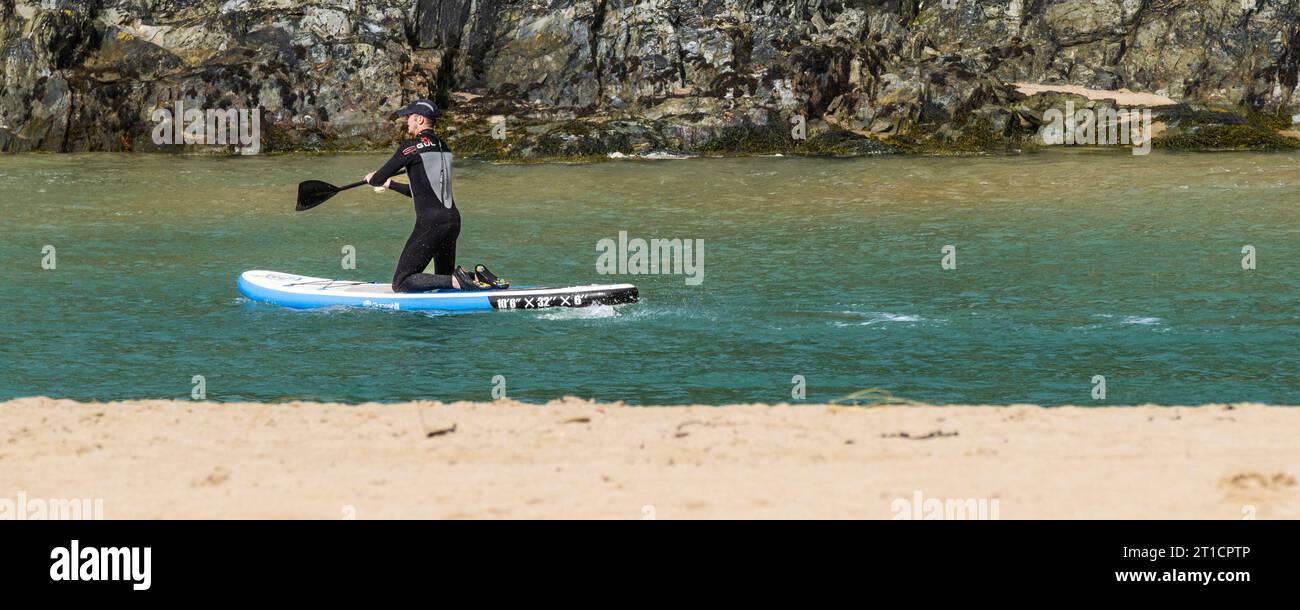 A panoramic image of a holidaymaker kneeling on a paddleboard on the ...