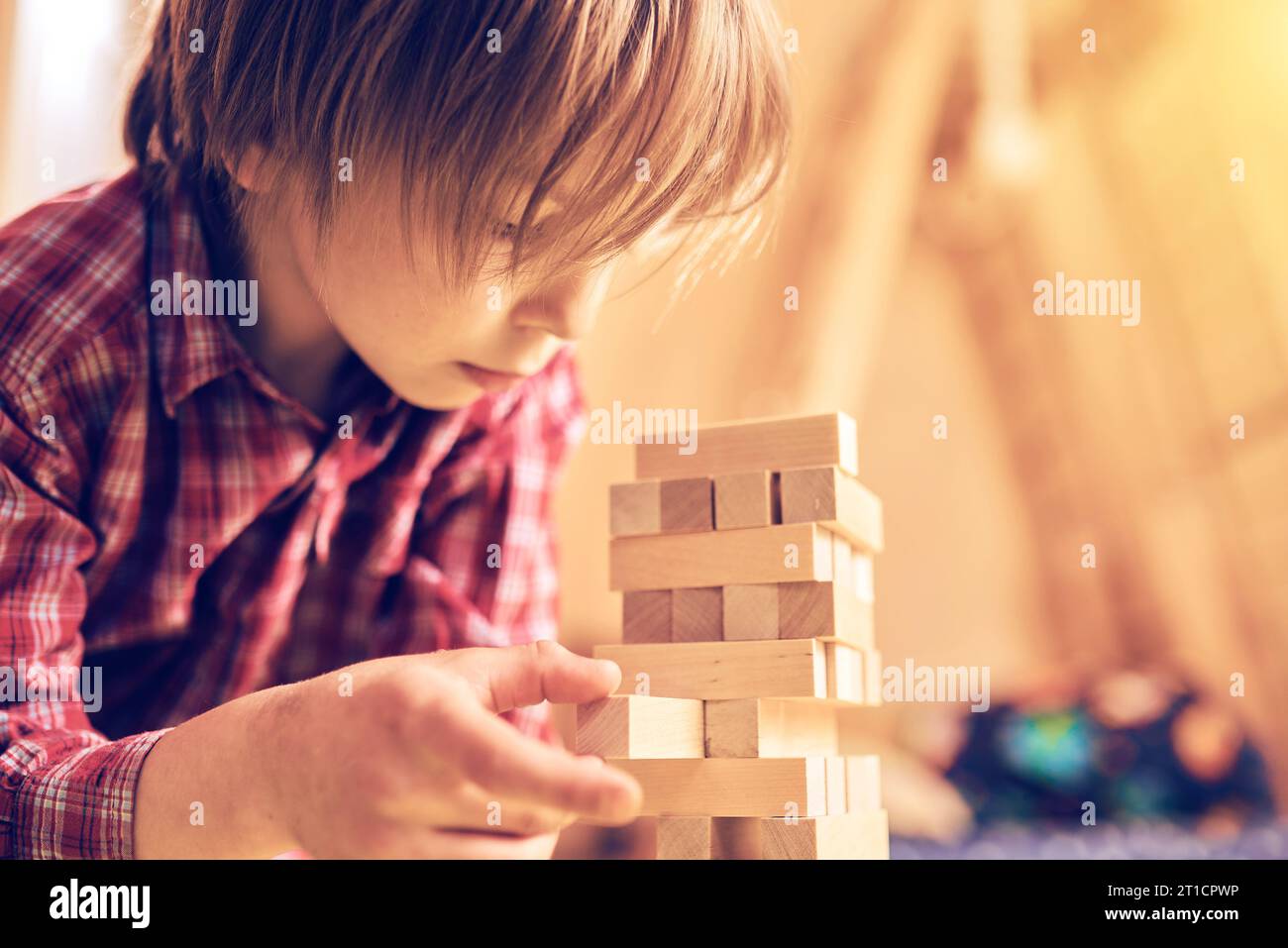 Preschool cute boy playing in a table game with wooden blocks at home ...
